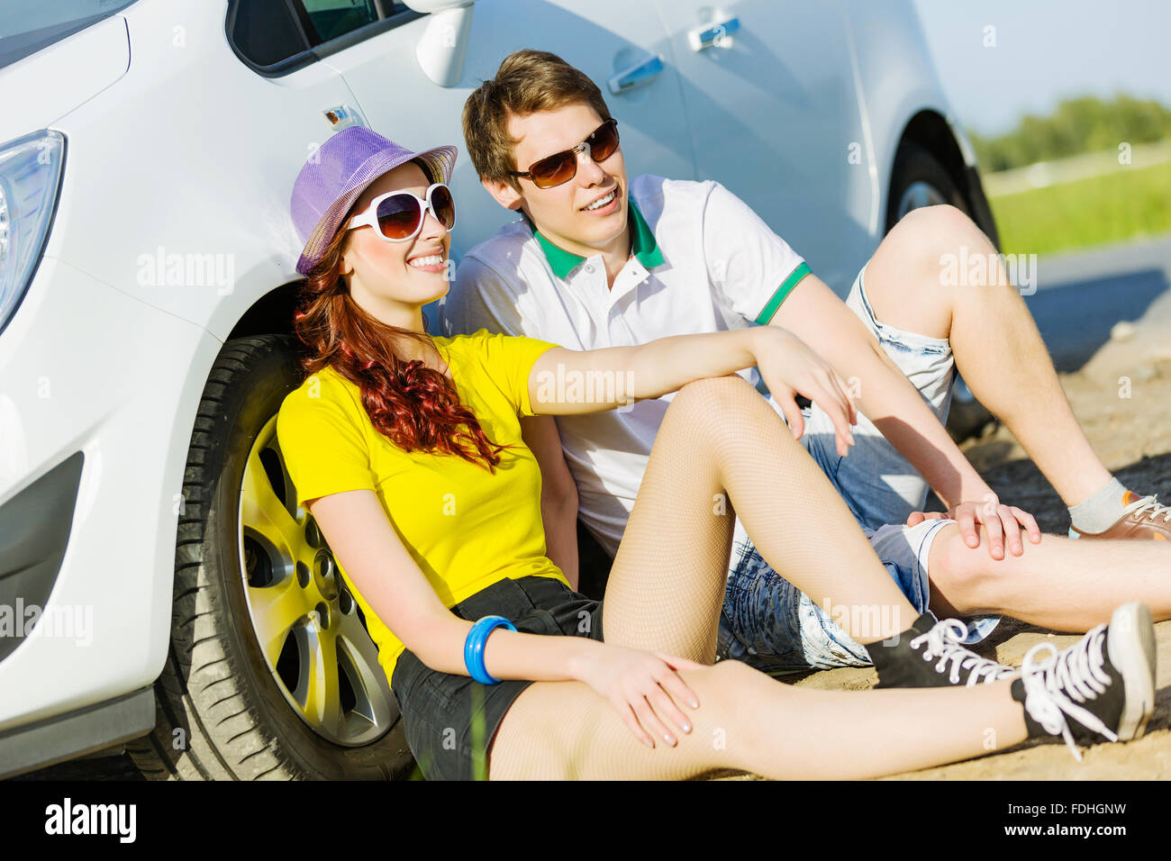 Young people sitting near car aside of road Stock Photo - Alamy