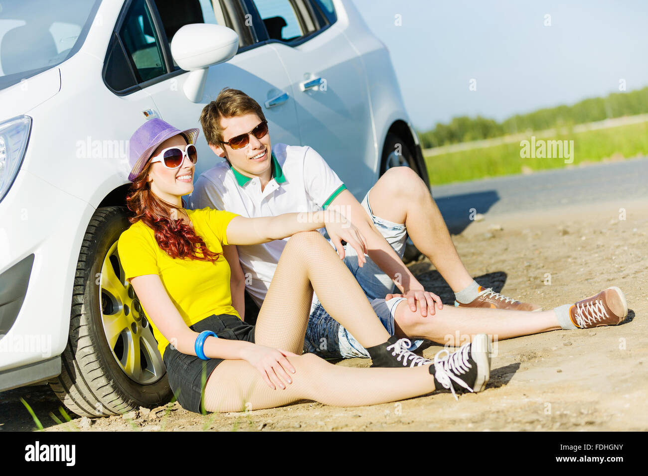 Young people sitting near car aside of road Stock Photo - Alamy