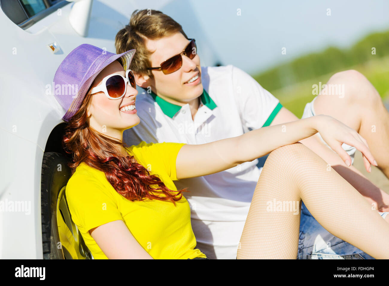 Young people sitting near car aside of road Stock Photo - Alamy