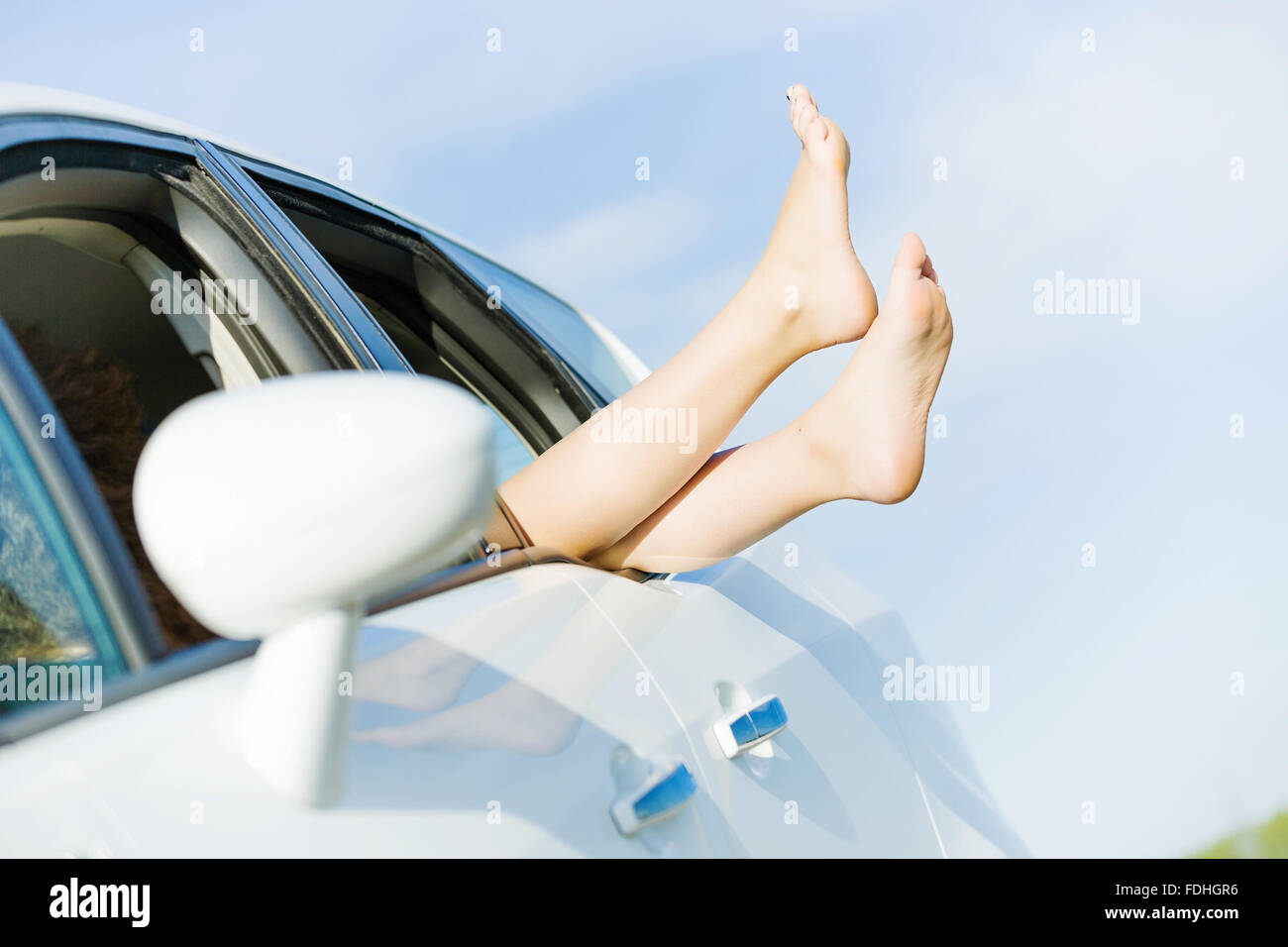 Feet of woman leaned out of car window Stock Photo - Alamy