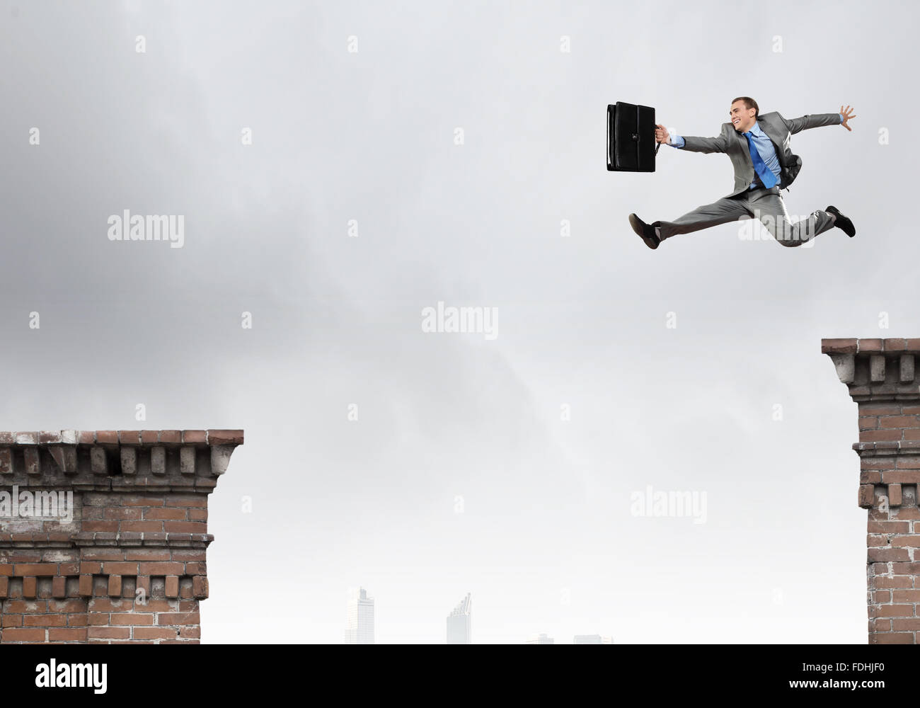 Young successful businessman jumping over gap. Risk and challenge ...