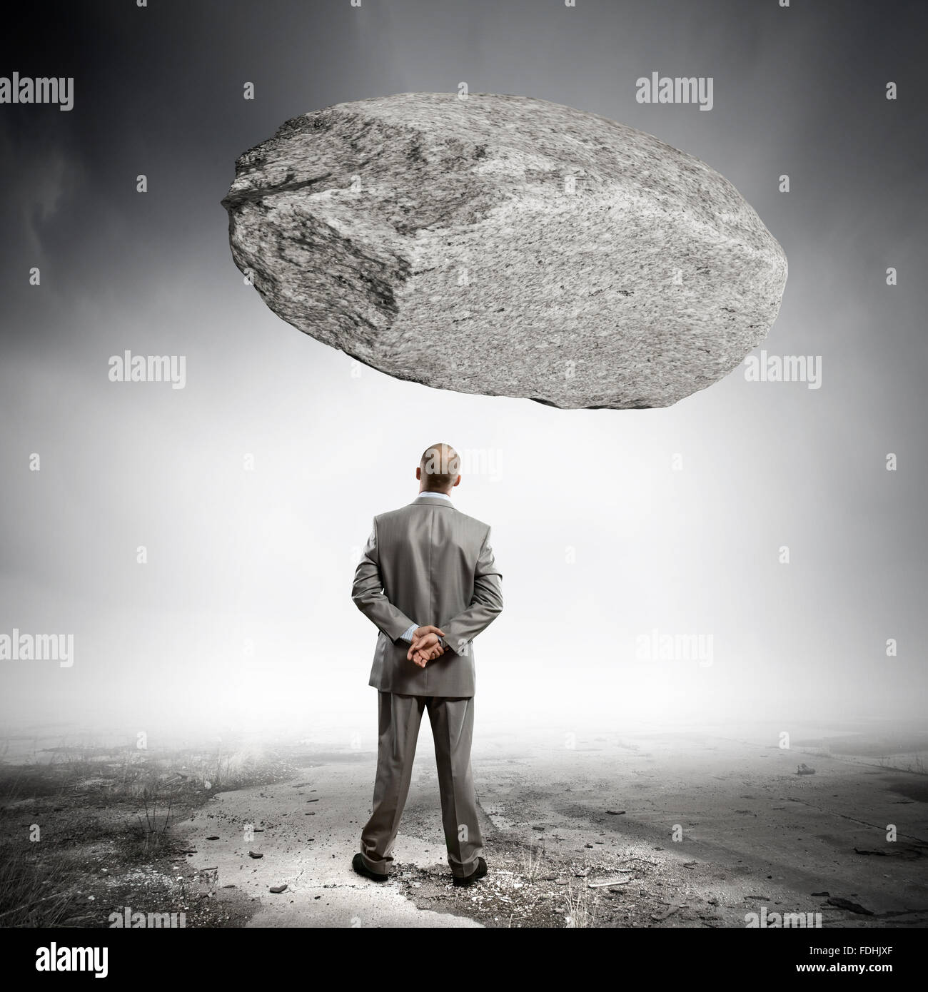 Rear view of confident businessman with huge stone above Stock Photo ...