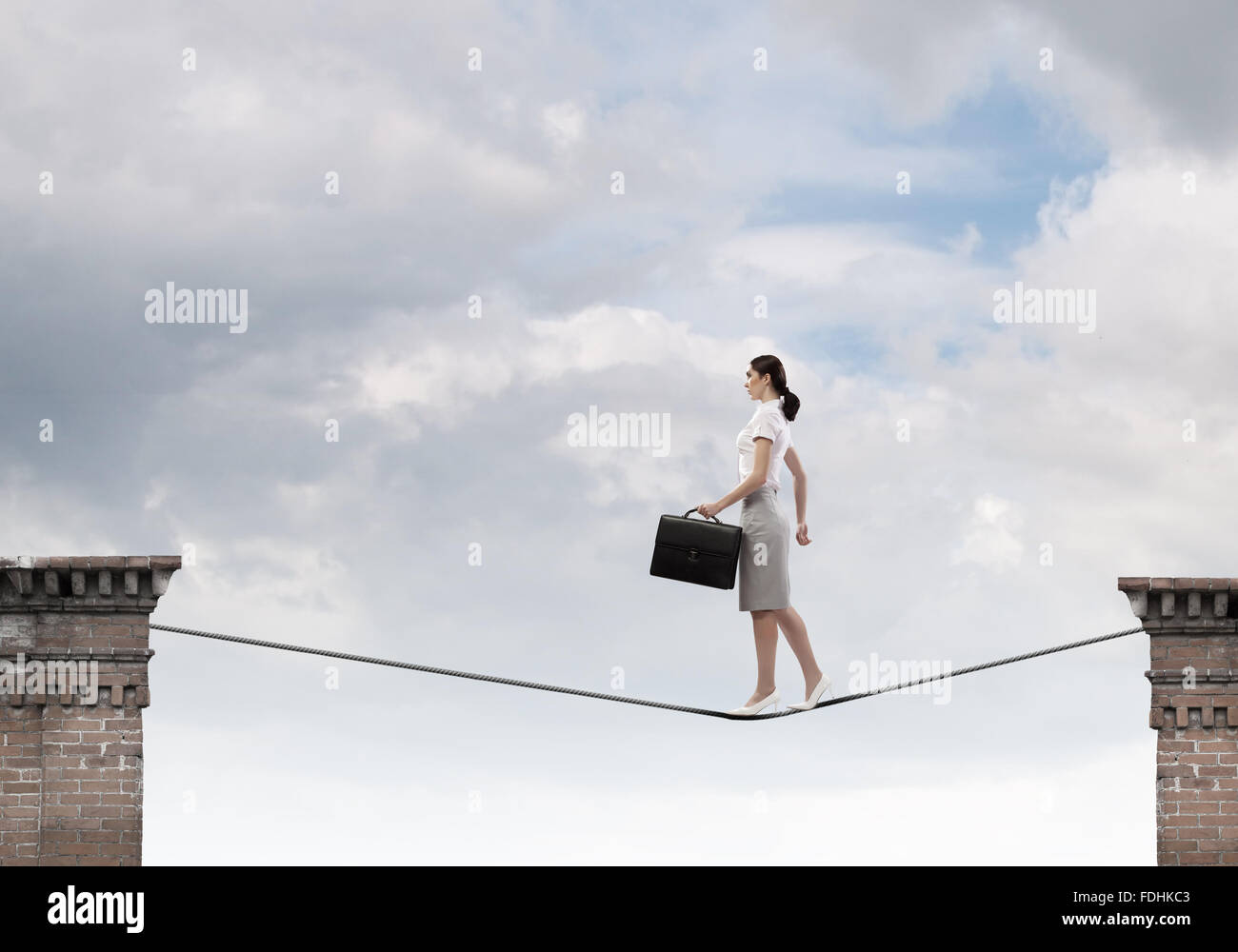Young confident businesswoman walking on rope above gap Stock Photo - Alamy