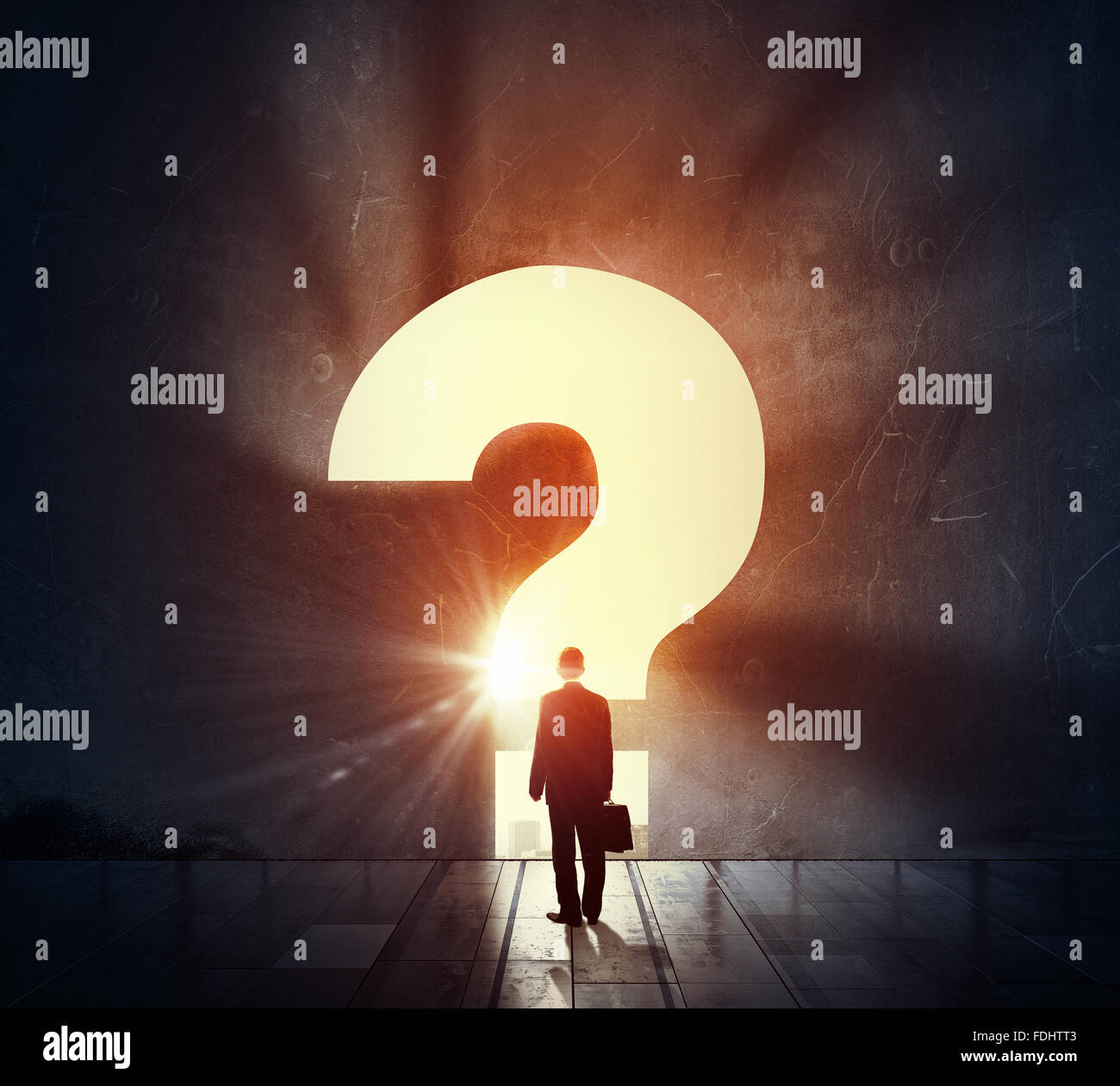 Back view of businessman standing in light of big question mark Stock ...