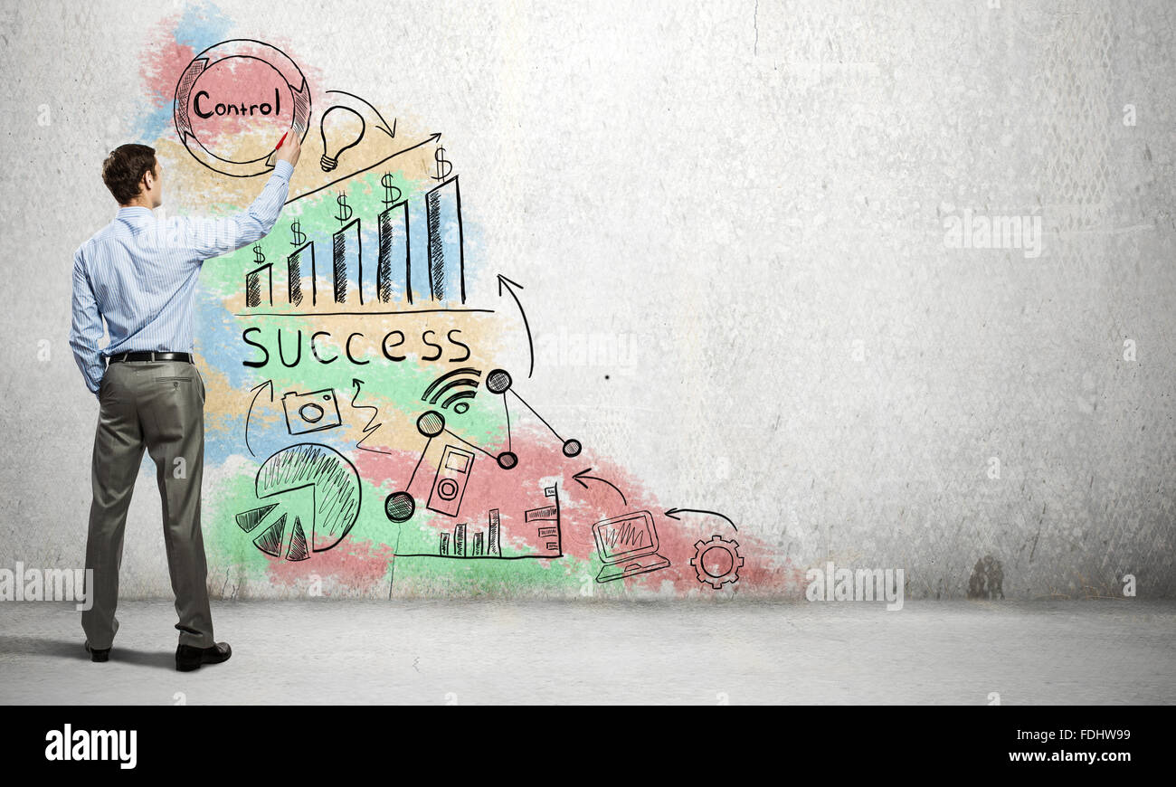 Back view of businessman drawing business sketches on wall Stock Photo ...