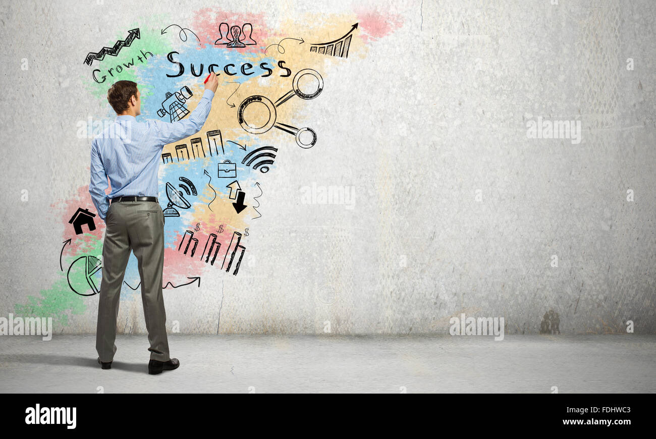 Back view of businessman drawing business sketches on wall Stock Photo ...