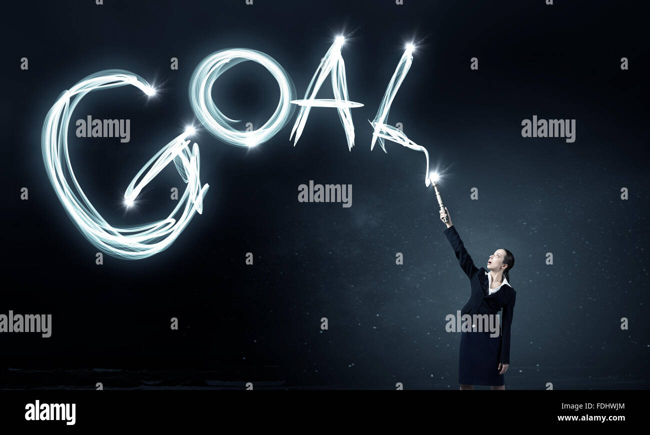 Businesswoman in darkness drawing goal word with flashlight Stock Photo ...