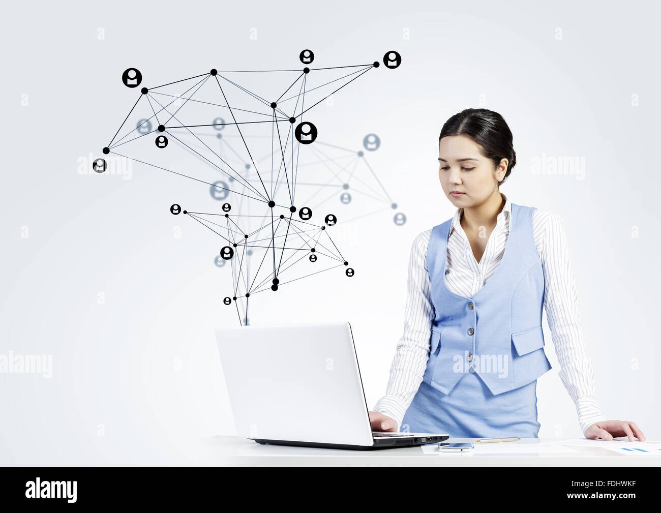 Beautiful young lady at desk working on laptop with social network ...