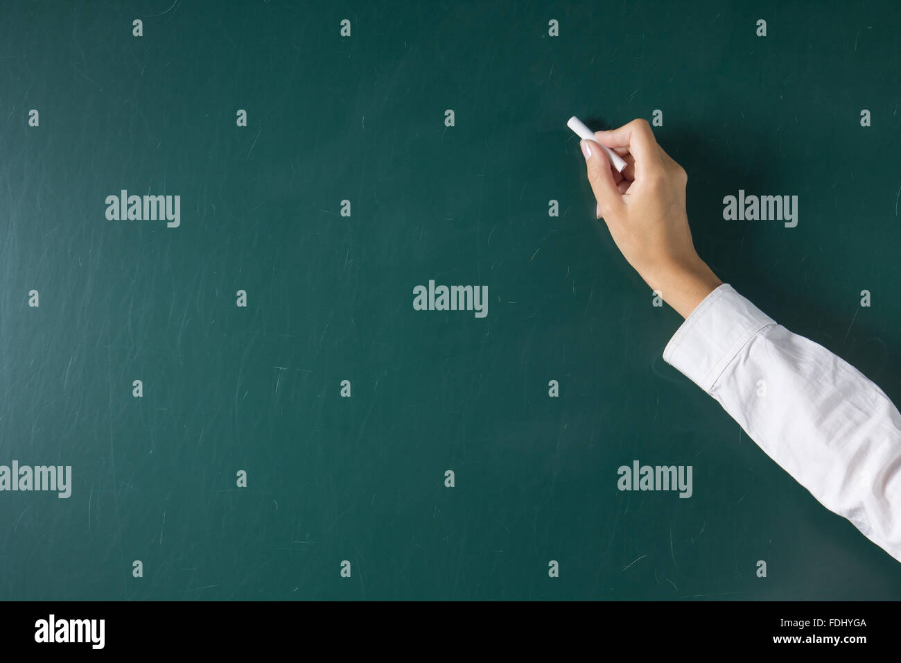 Female hand writing with a piece of chalk on the blackboard or ...