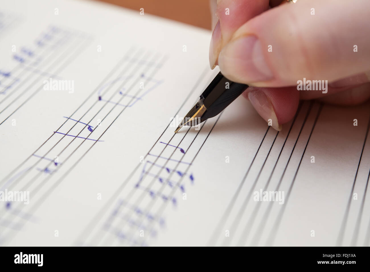 Hand with pen and music sheet Stock Photo - Alamy