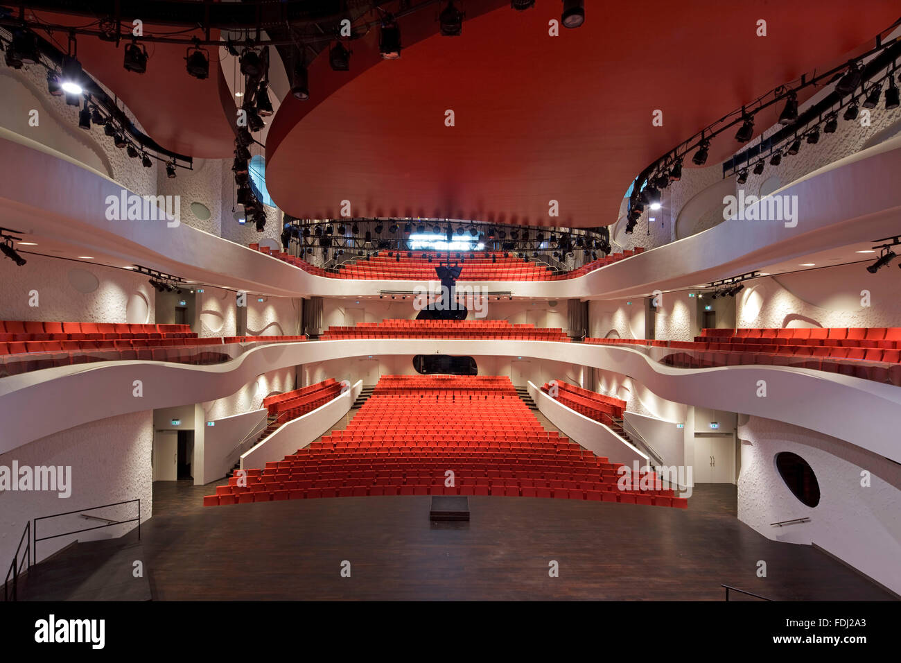 Main hall, with red seating against curving white walls and balconies ...