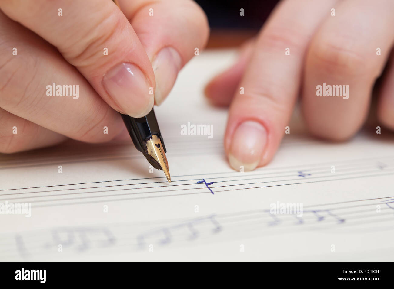 Hand with pen and music sheet Stock Photo - Alamy