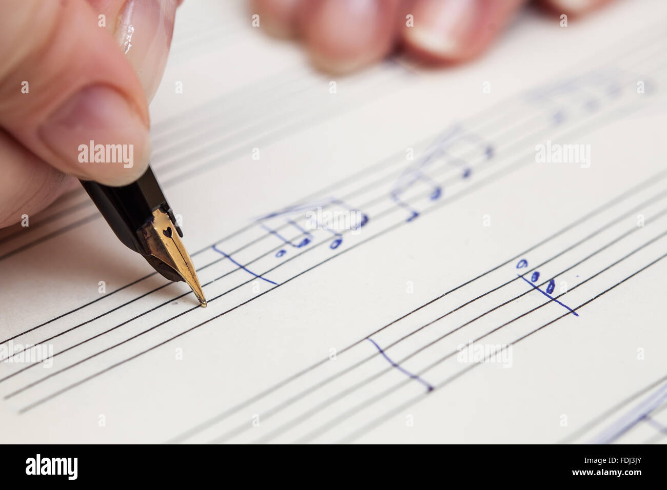 Hand with pen and music sheet Stock Photo - Alamy