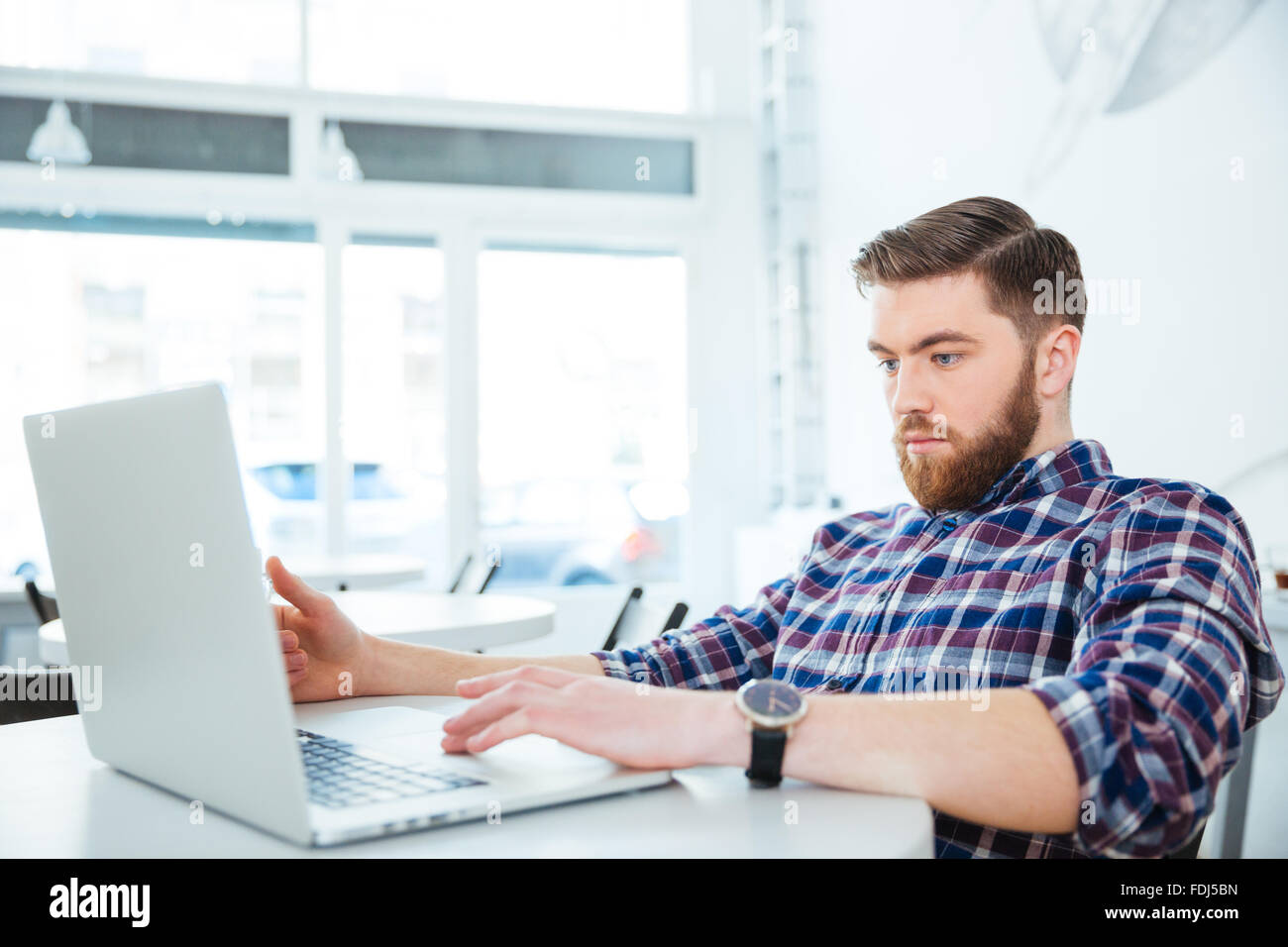 Handsome man sitting at the table with laptop computer in coffee shop ...