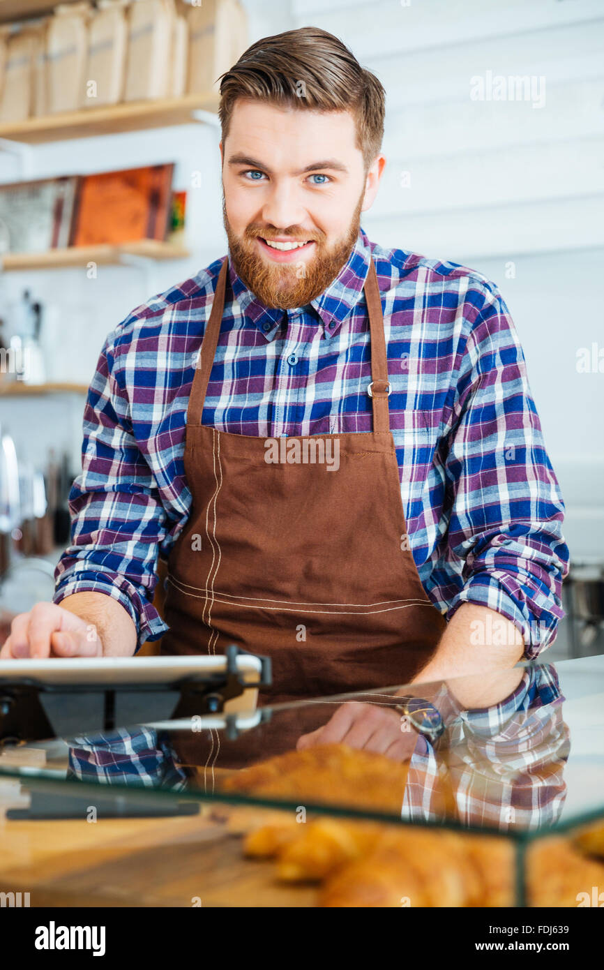 Potrait of attractive happy bearded barista in brown apron at work in ...