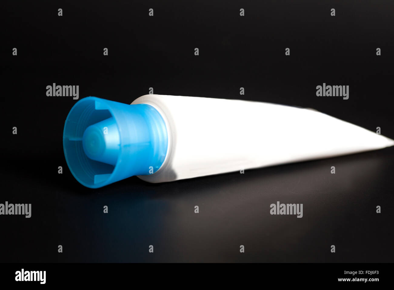 White toothpaste tube on black background Stock Photo - Alamy