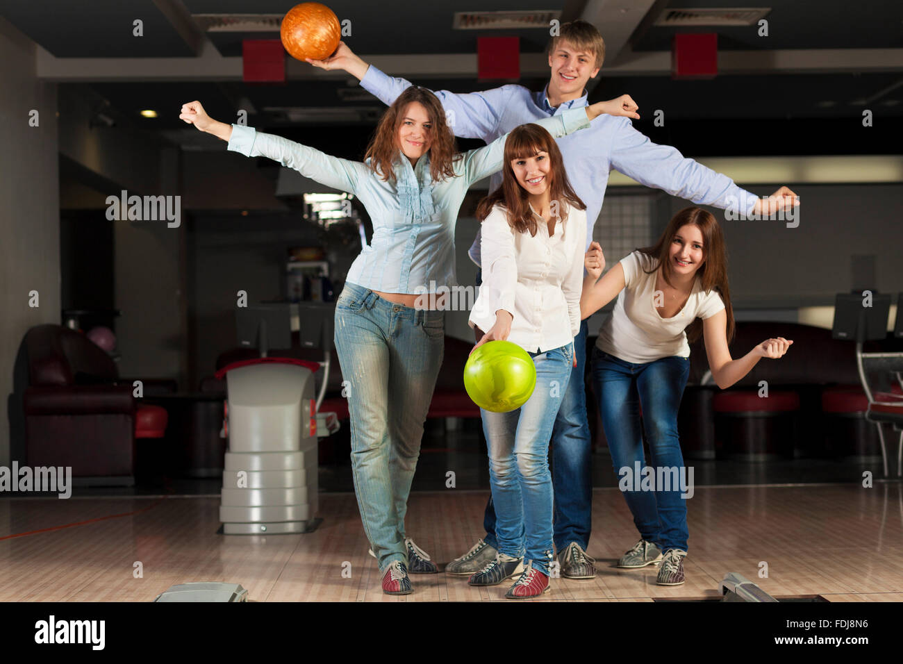 Group of four young smiling people playing bowling Stock Photo - Alamy