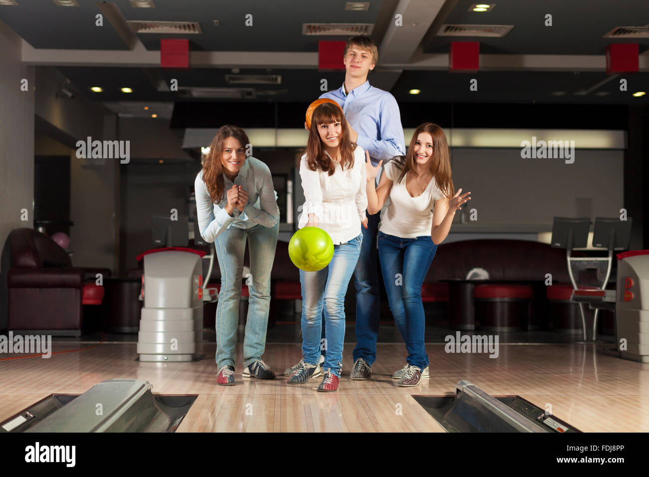Group of four young smiling people playing bowling Stock Photo - Alamy