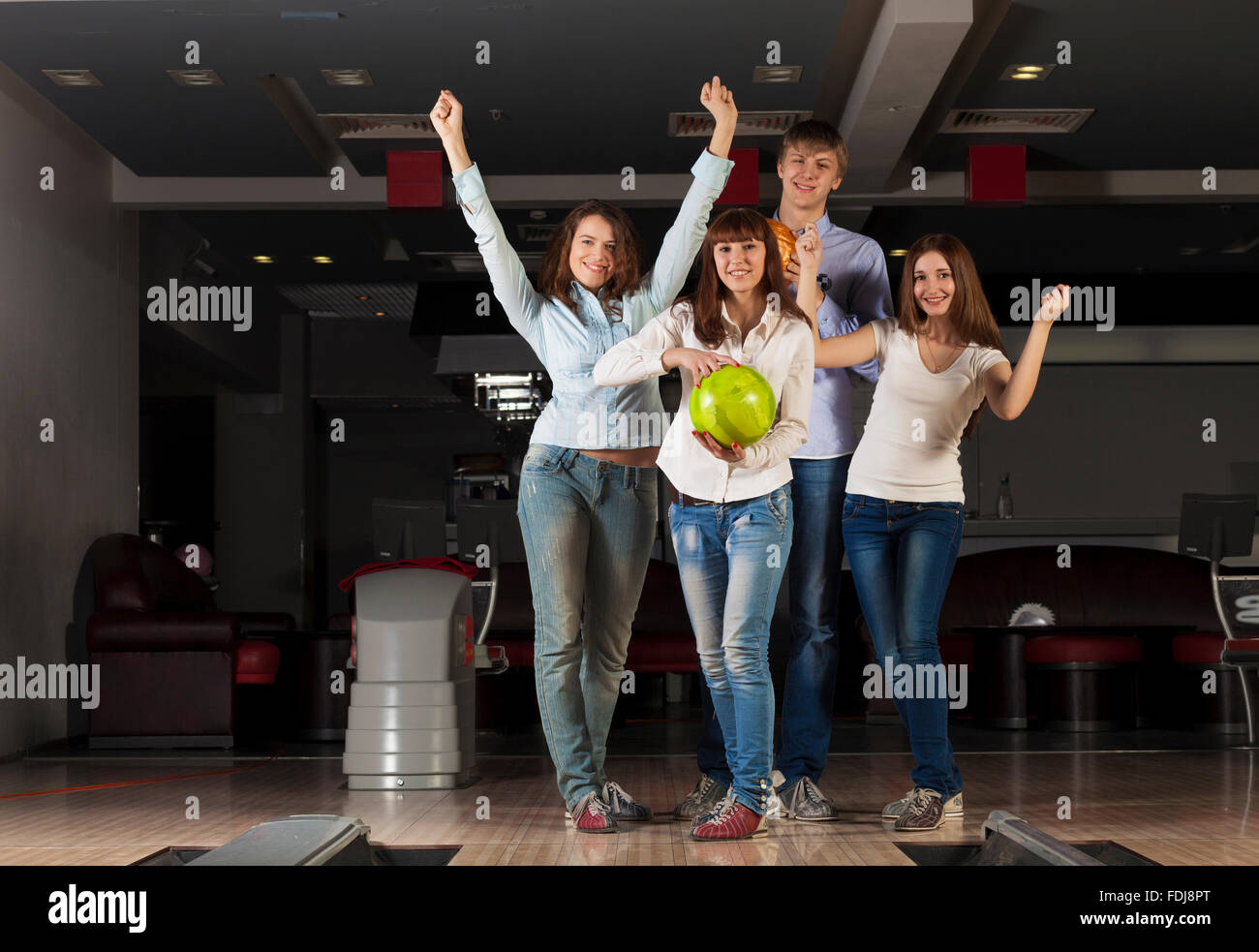 Group of four young smiling people playing bowling Stock Photo - Alamy