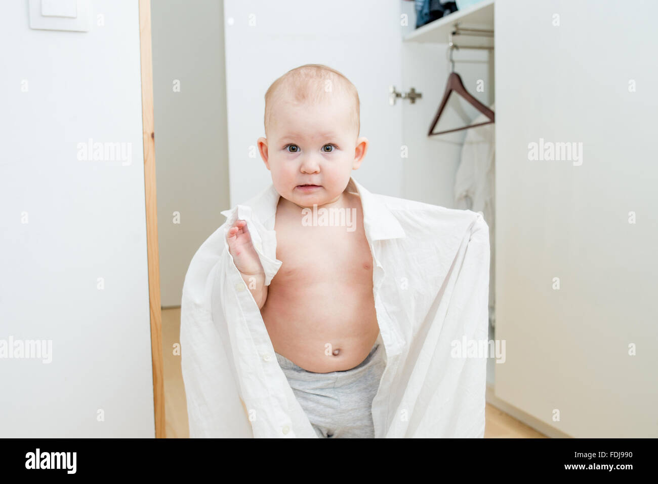 little child trying on clothes. He wants to dress white shirt Stock ...