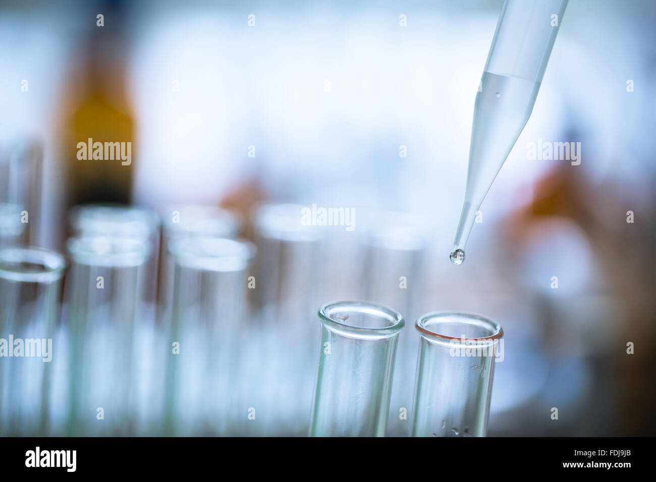 Liquid drop from laboratory glass pipette to test tube Stock Photo - Alamy