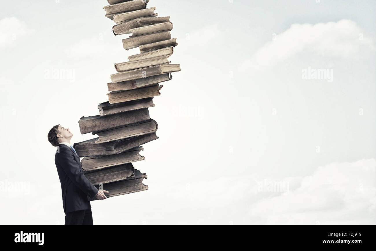 Young businessman carrying stack of old books in his hands Stock Photo ...