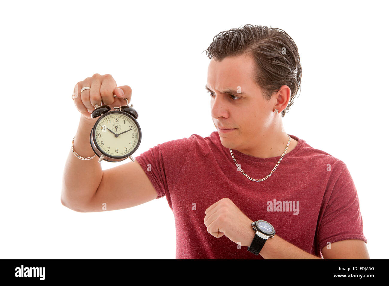 Young man is angry at alarm clock over white background Stock Photo - Alamy