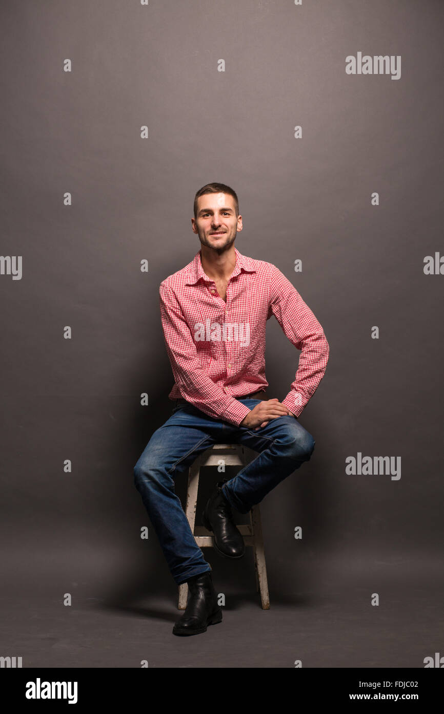 Handsome man sitting on a chair in studio Stock Photo - Alamy
