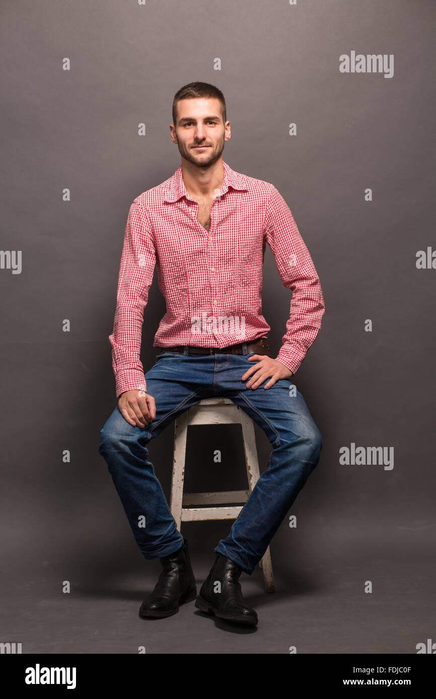 Handsome man sitting on a chair in studio Stock Photo - Alamy