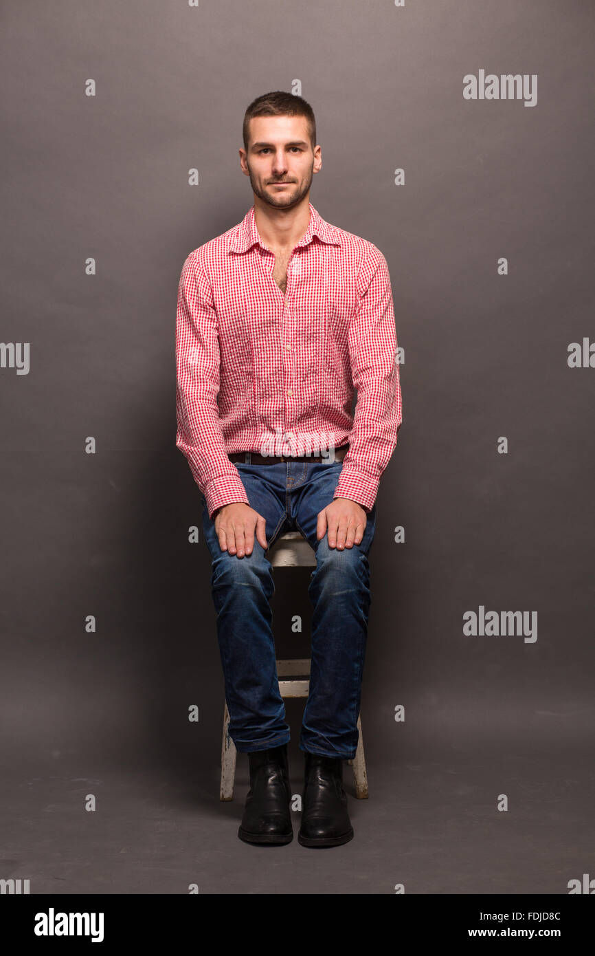 Handsome man sitting on a chair in studio Stock Photo - Alamy