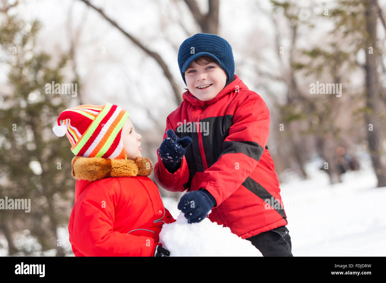 Cute boy and girl building snowman in winter park Stock Photo - Alamy