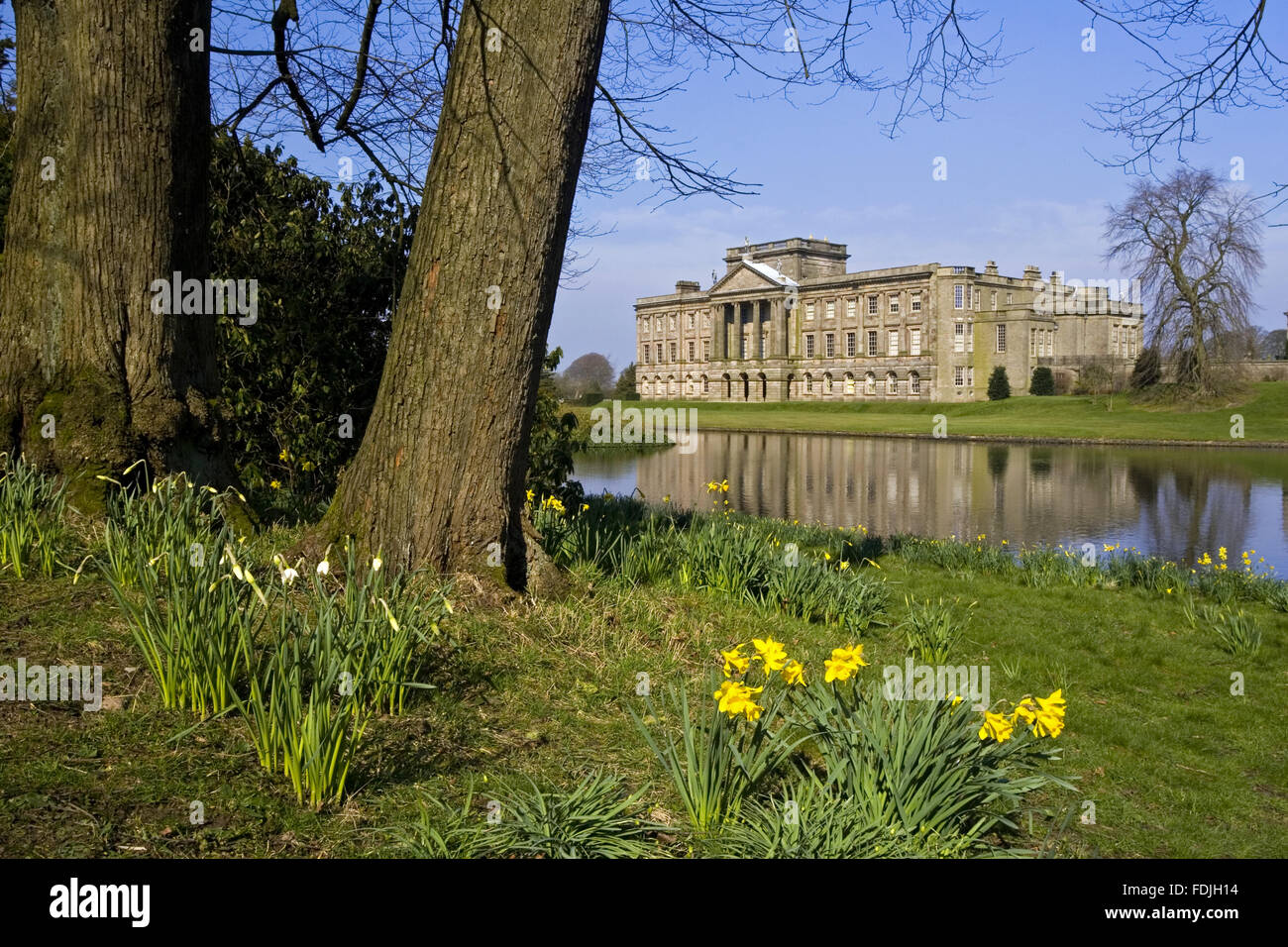 The south front of Lyme Park seen across the lake, in springtime. The ...