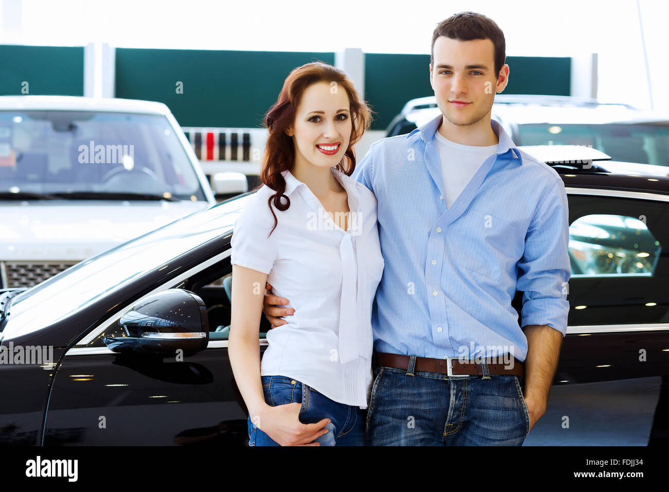 Two pretty young people smiling standing near car Stock Photo - Alamy