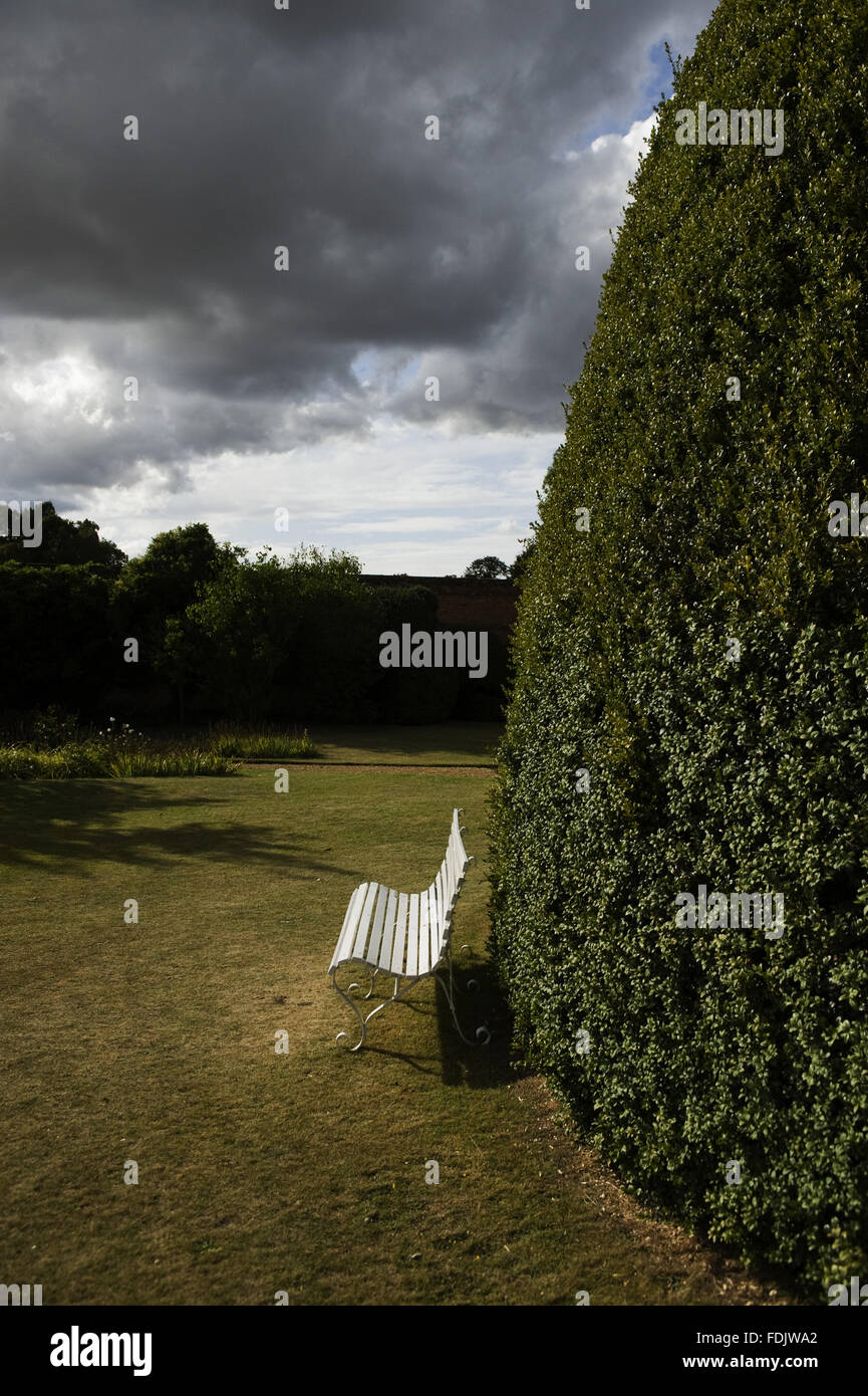 Ornamental white bench against yew topiary in the garden at Melford ...