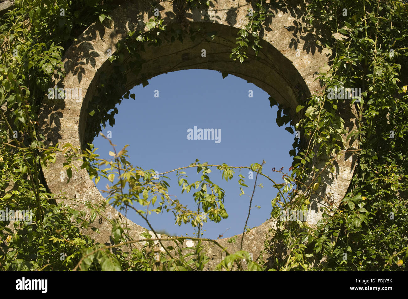 Glimpse of blue sky through a circular window in the garden wall at ...