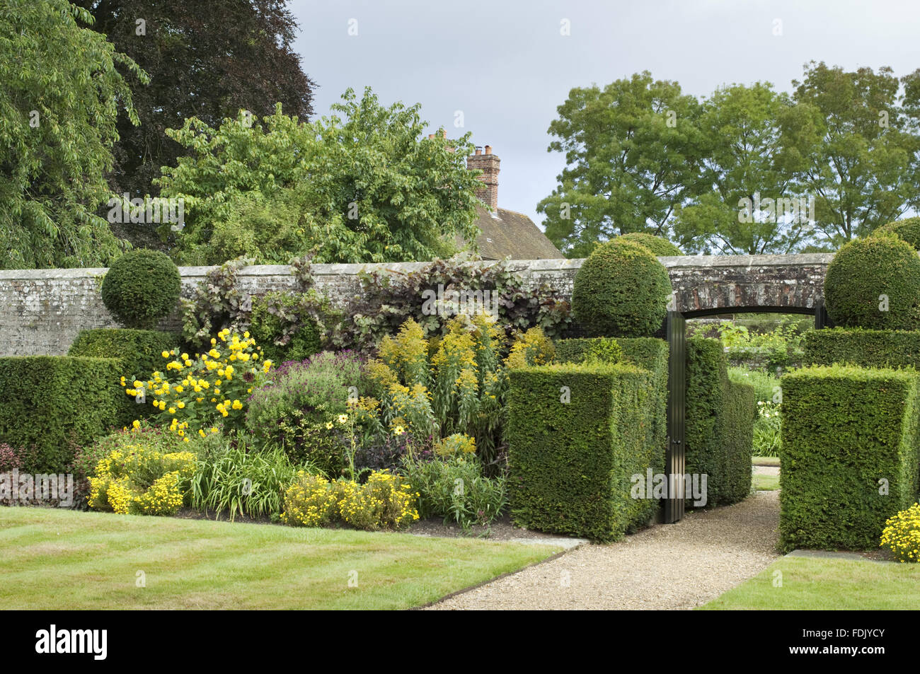 Late summer planting and topiary hedging flanking the gate to the ...
