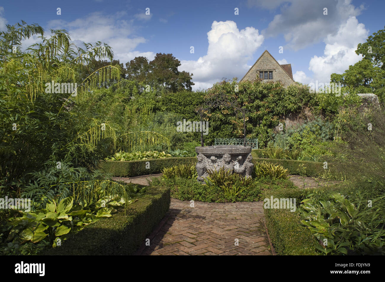 Wellhead surrounded by lush foliage planting in part of the garden ...
