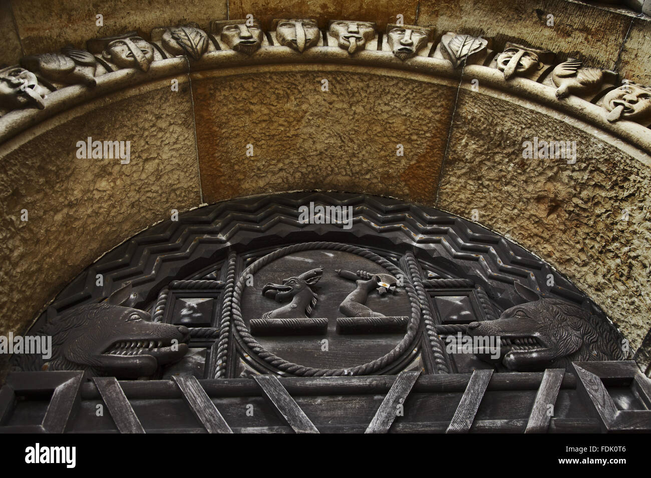 Neo-Norman stonework carving around the door with metalwork crests of ...