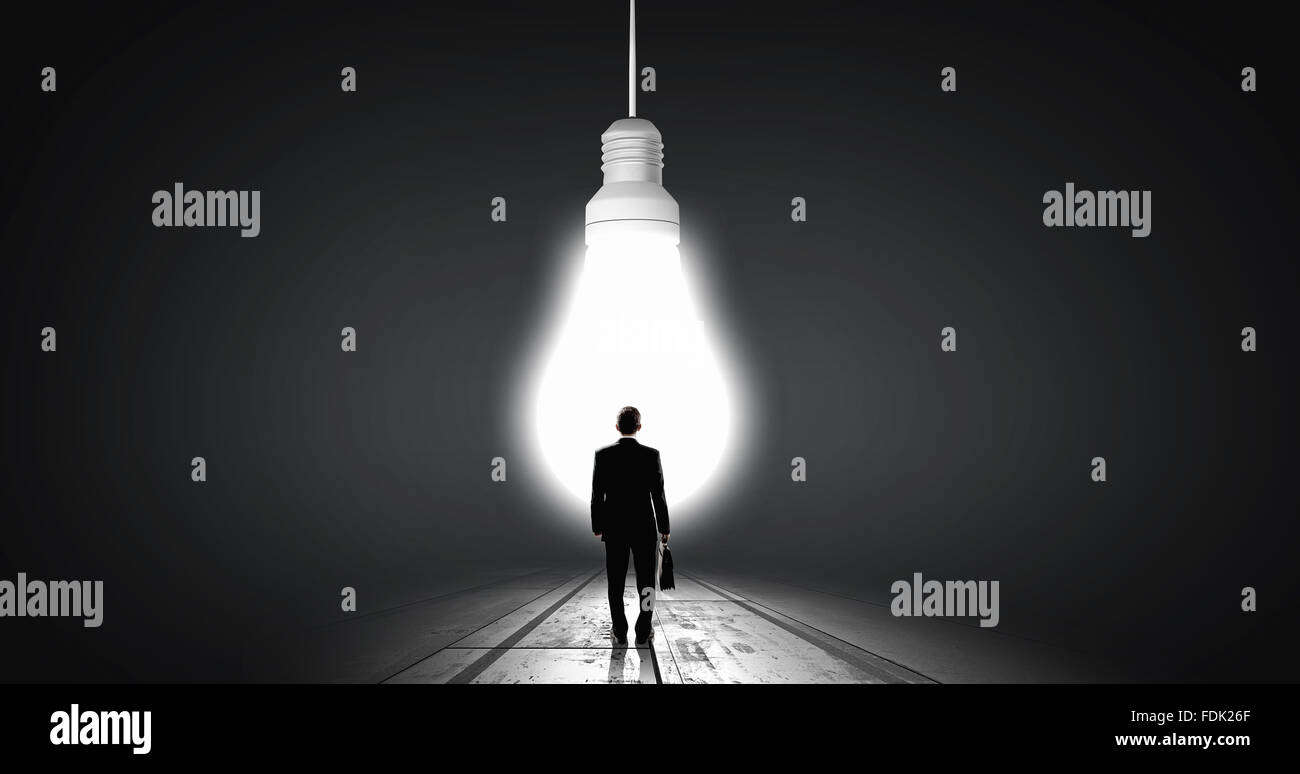 Back view of businessman looking at big glowing light bulb Stock Photo ...
