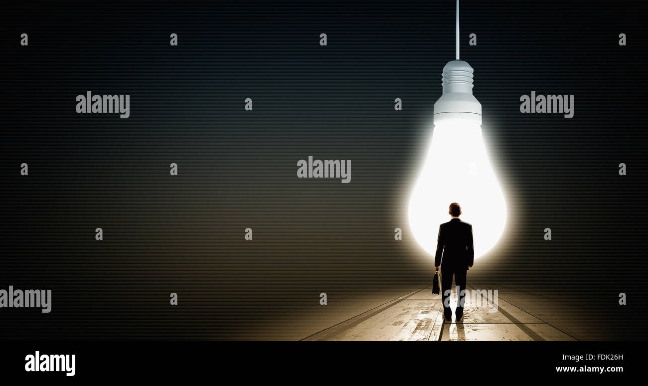 Back view of businessman looking at big glowing light bulb Stock Photo ...