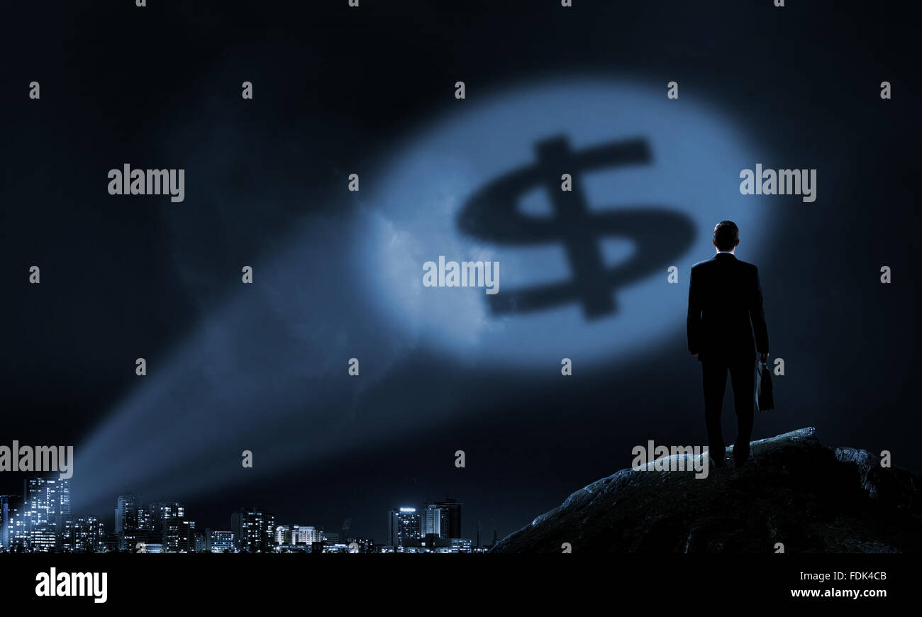 Businessman standing with back in darkness and dollar sign in ...