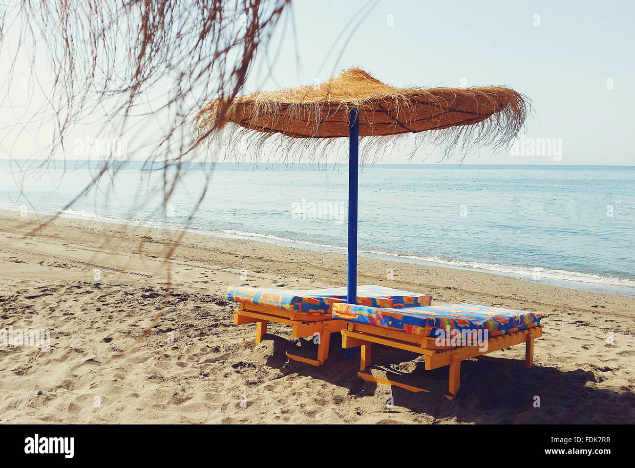 Straw parasol and two sun loungers on the beach Stock Photo - Alamy