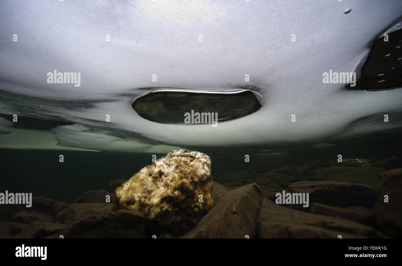 Underwater landscape in a mountain lake with ice and a quartz boulder ...