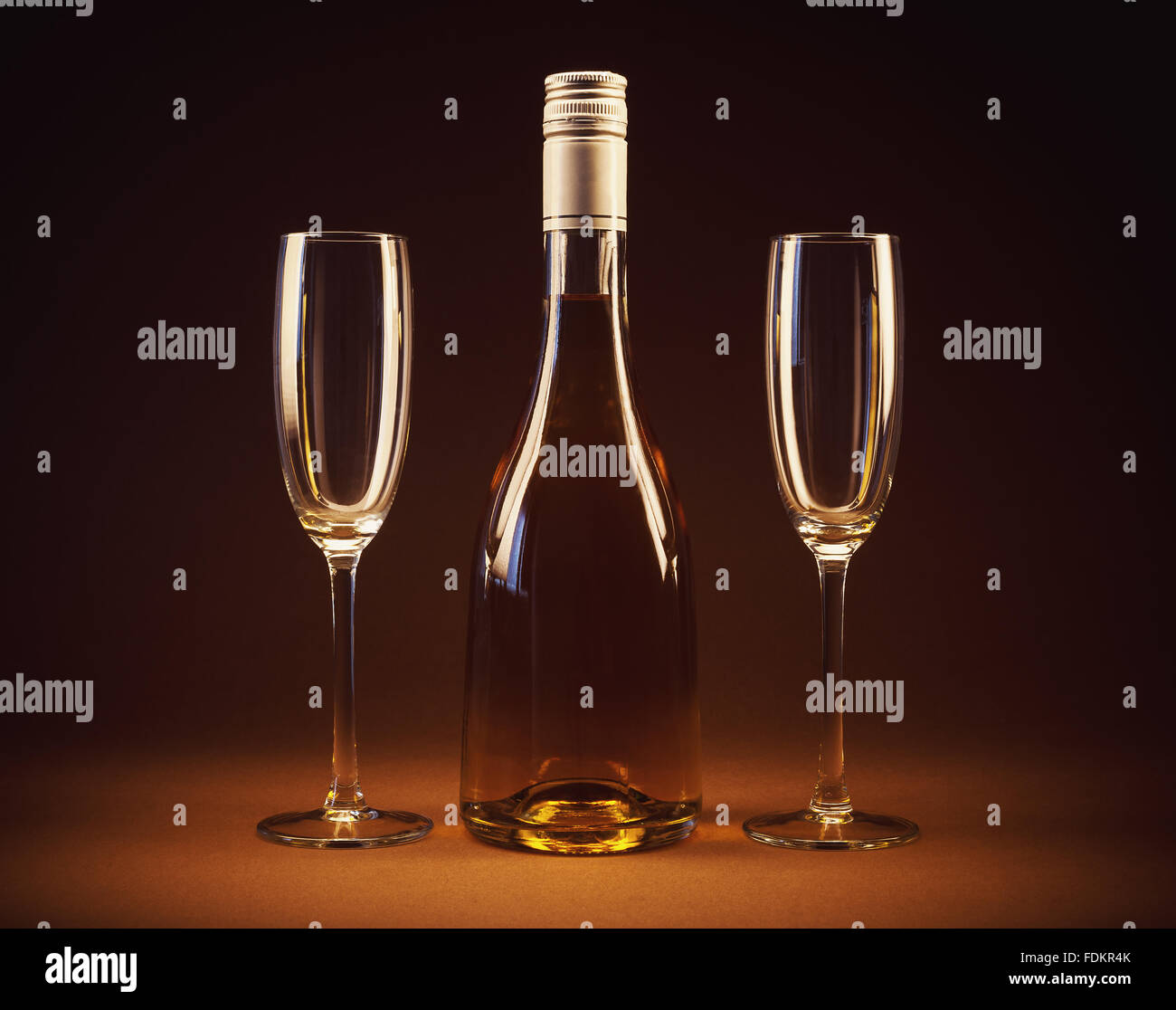 Two empty glasses and a bottle of spirit drink on brown background ...