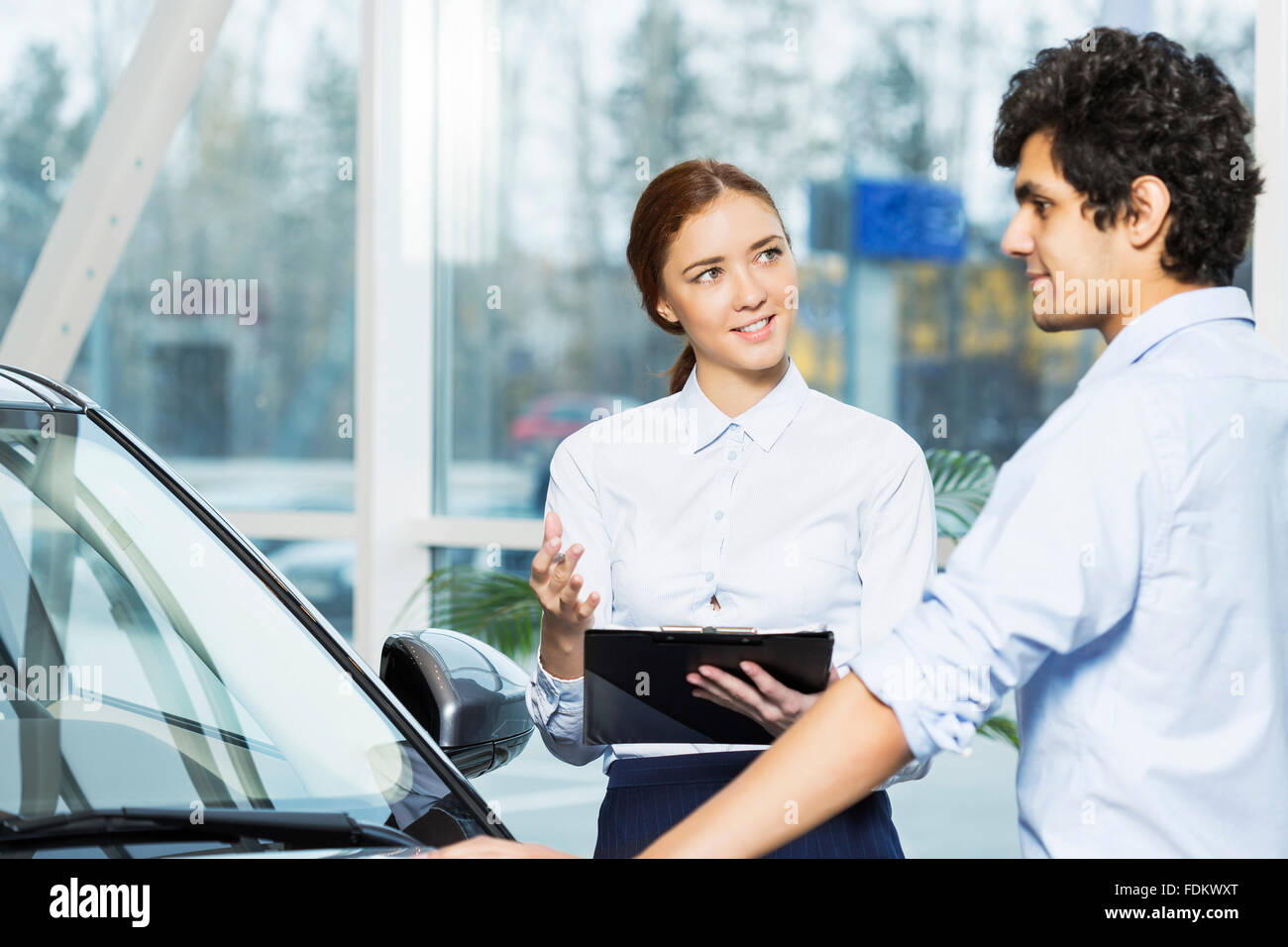 Young woman dealer in auto salon presenting car to customer Stock Photo ...