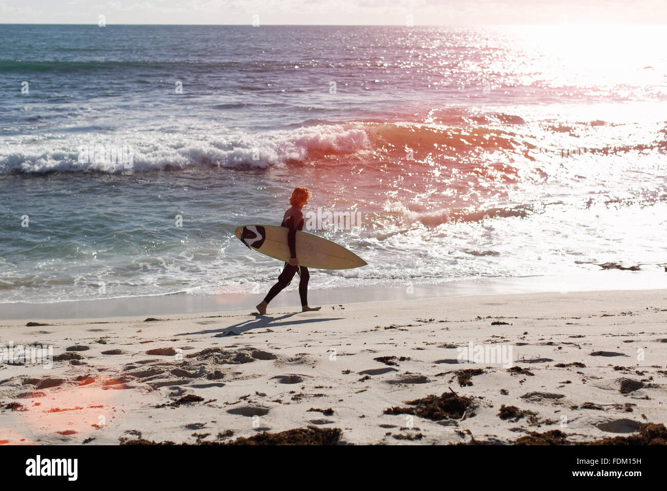 A surfer with his surfboard at the beach Stock Photo - Alamy