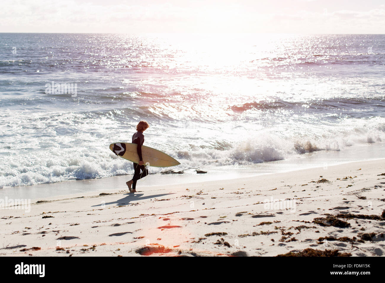 A surfer with his surfboard at the beach Stock Photo - Alamy