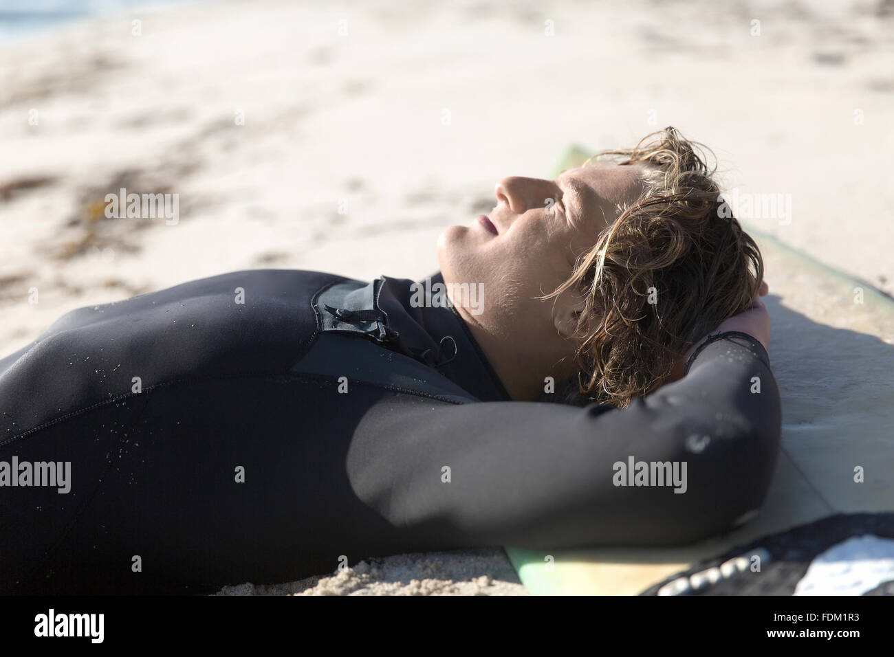 A surfer relaxing and lying on his surfboard at the beach Stock Photo ...
