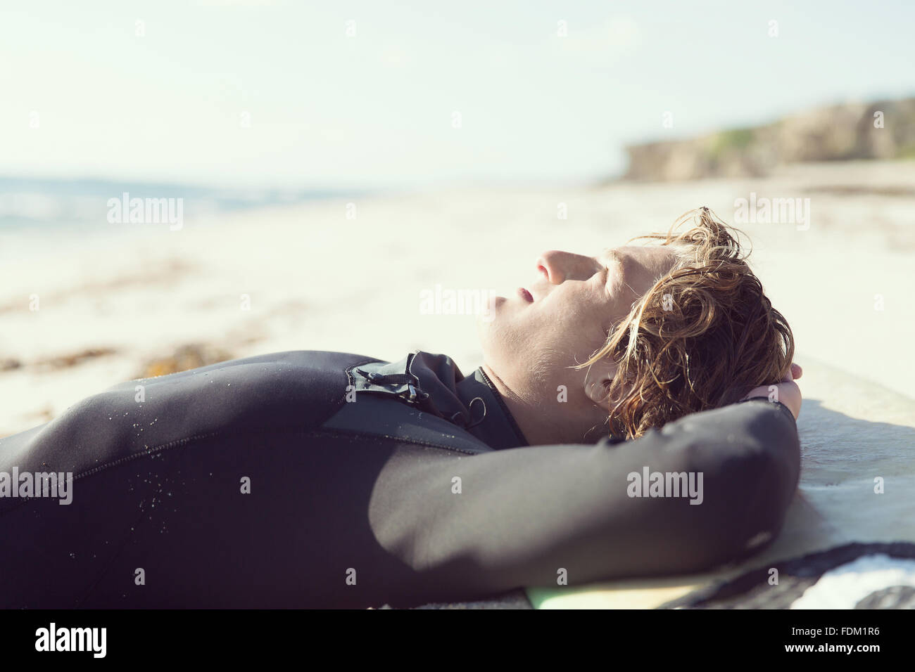 A surfer relaxing and lying on his surfboard at the beach Stock Photo ...