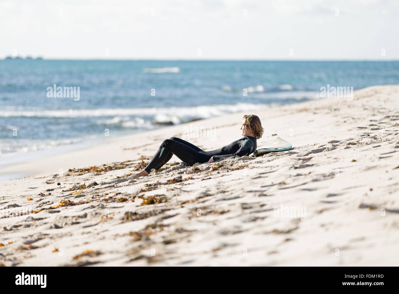 A surfer relaxing and lying on his surfboard at the beach Stock Photo ...